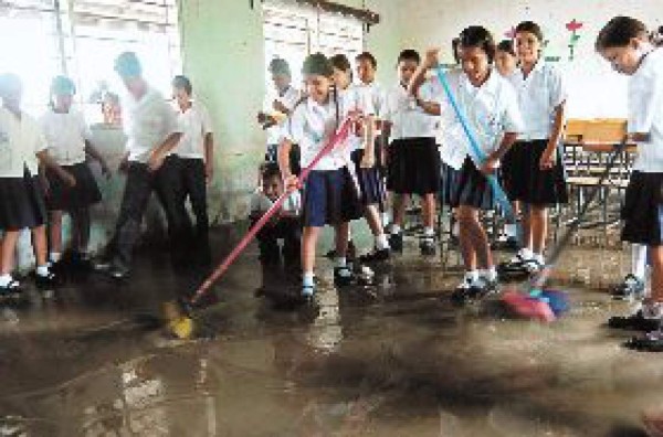Escolares lavan y limpian aulas inundadas